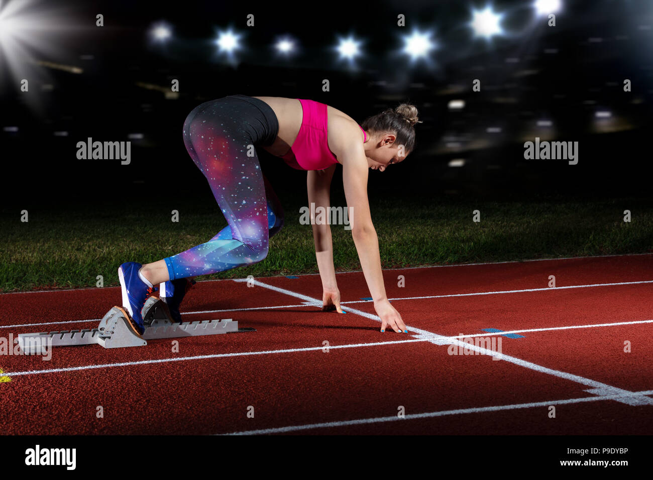 woman sprinter leaving starting blocks on the athletic track. exploding ...
