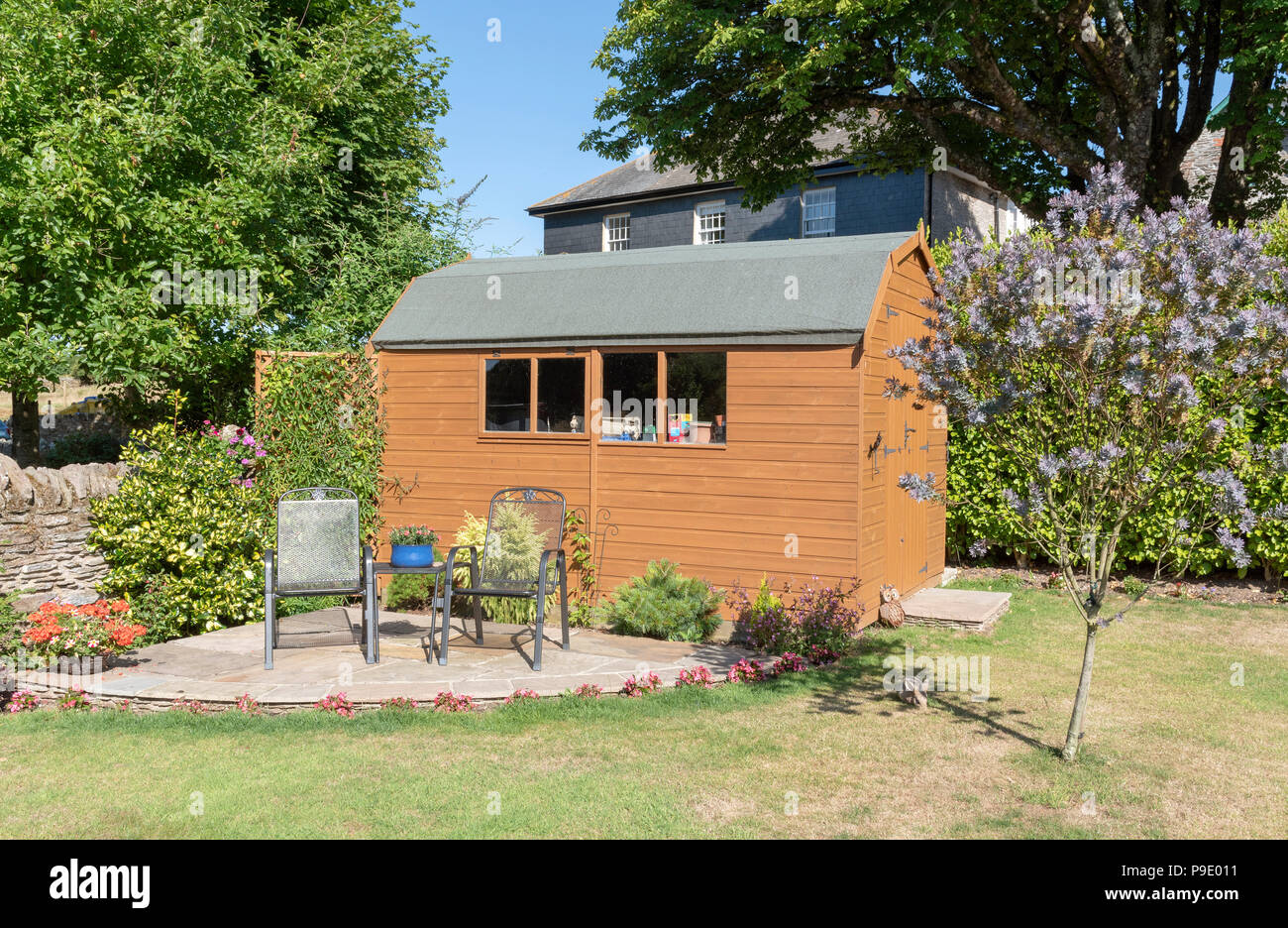 A Dutch style wooden garden shed with patio and two chairs Stock Photo ...