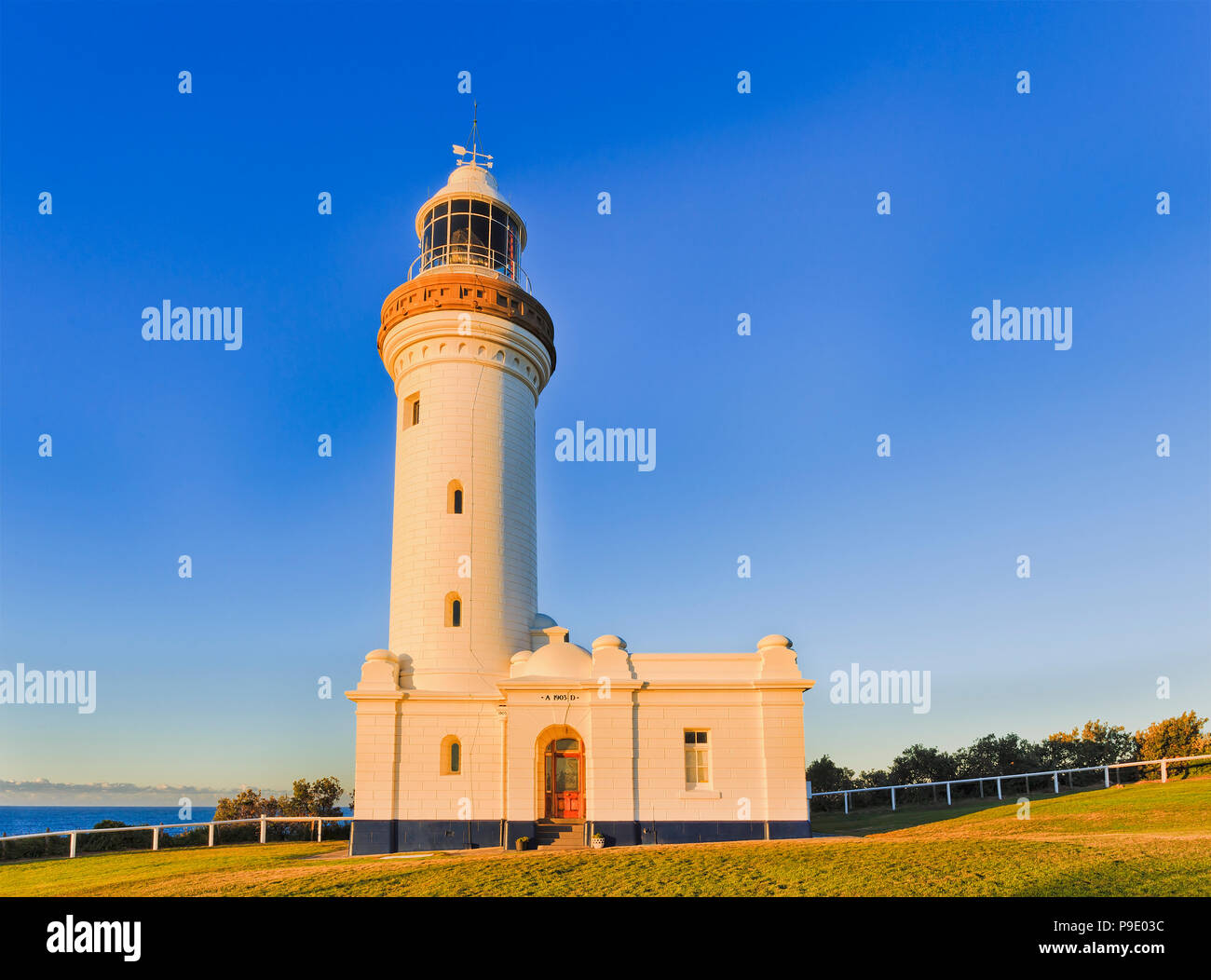 WHite snow historic Norah Head lighthouse under warm morning sun light ...