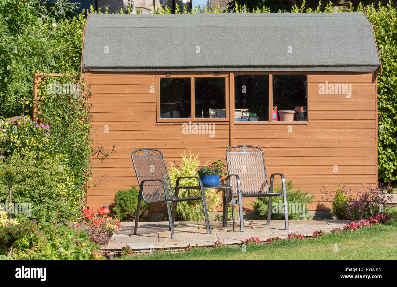 A Dutch style wooden garden shed with patio and two chairs Stock Photo ...