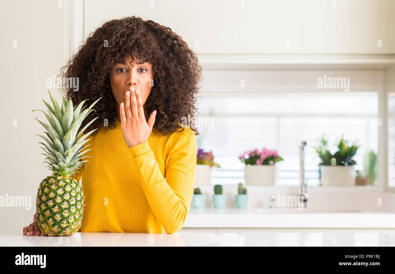 African american woman and pineapple tropical fruit cover mouth with ...