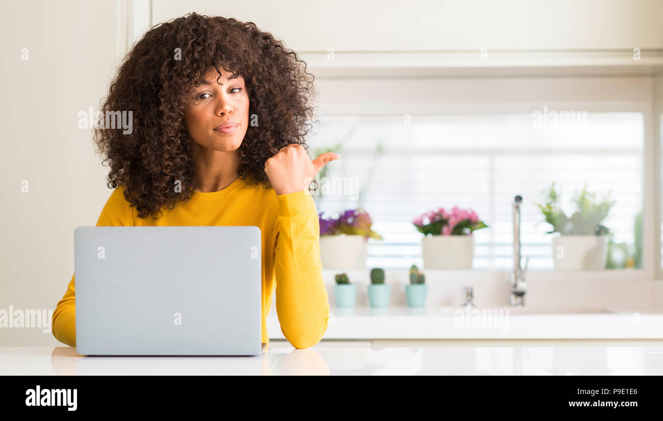 African american woman using computer laptop at kitchen pointing with ...