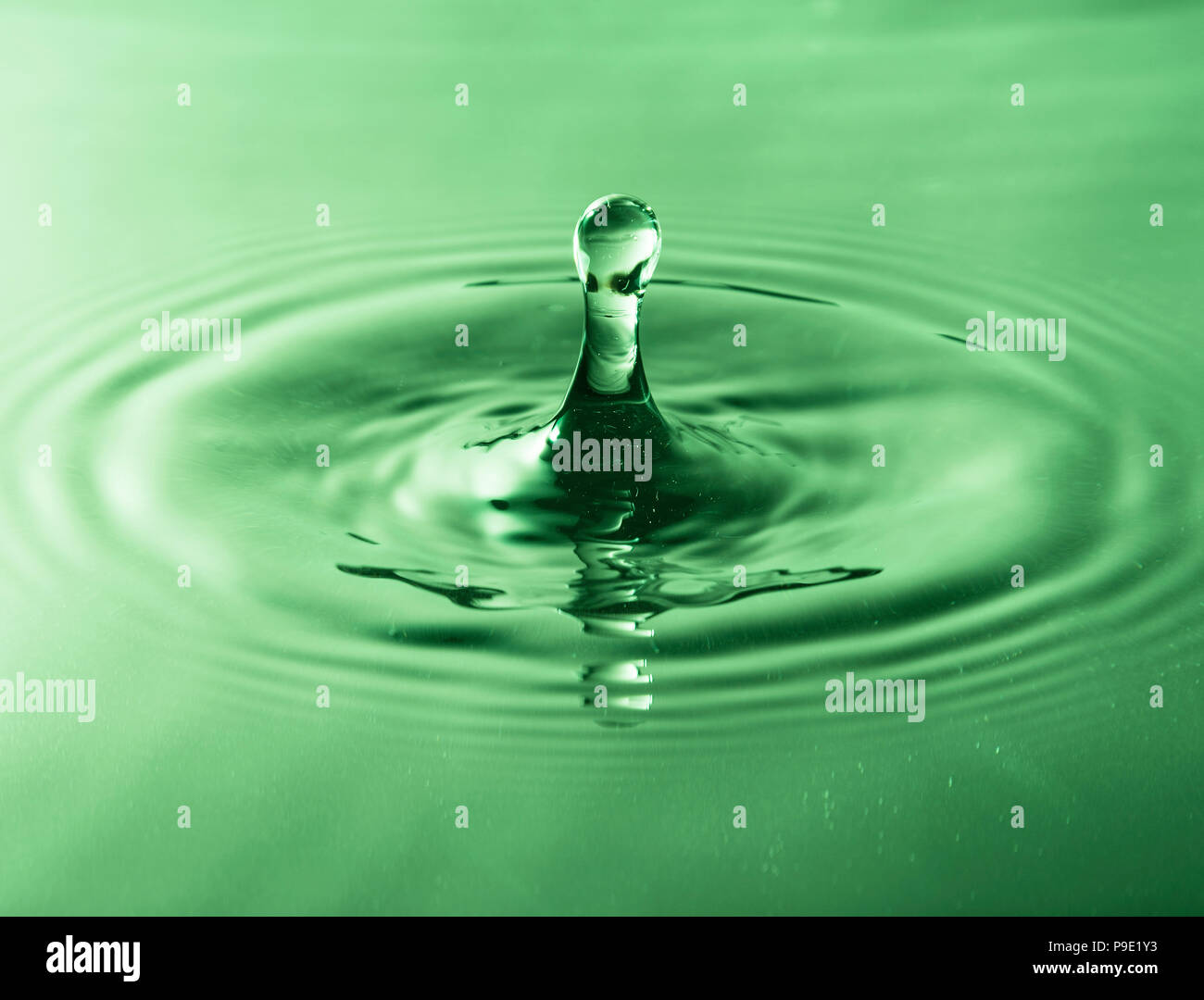 A small water drop fall on water surface and the splash jump to form a ...