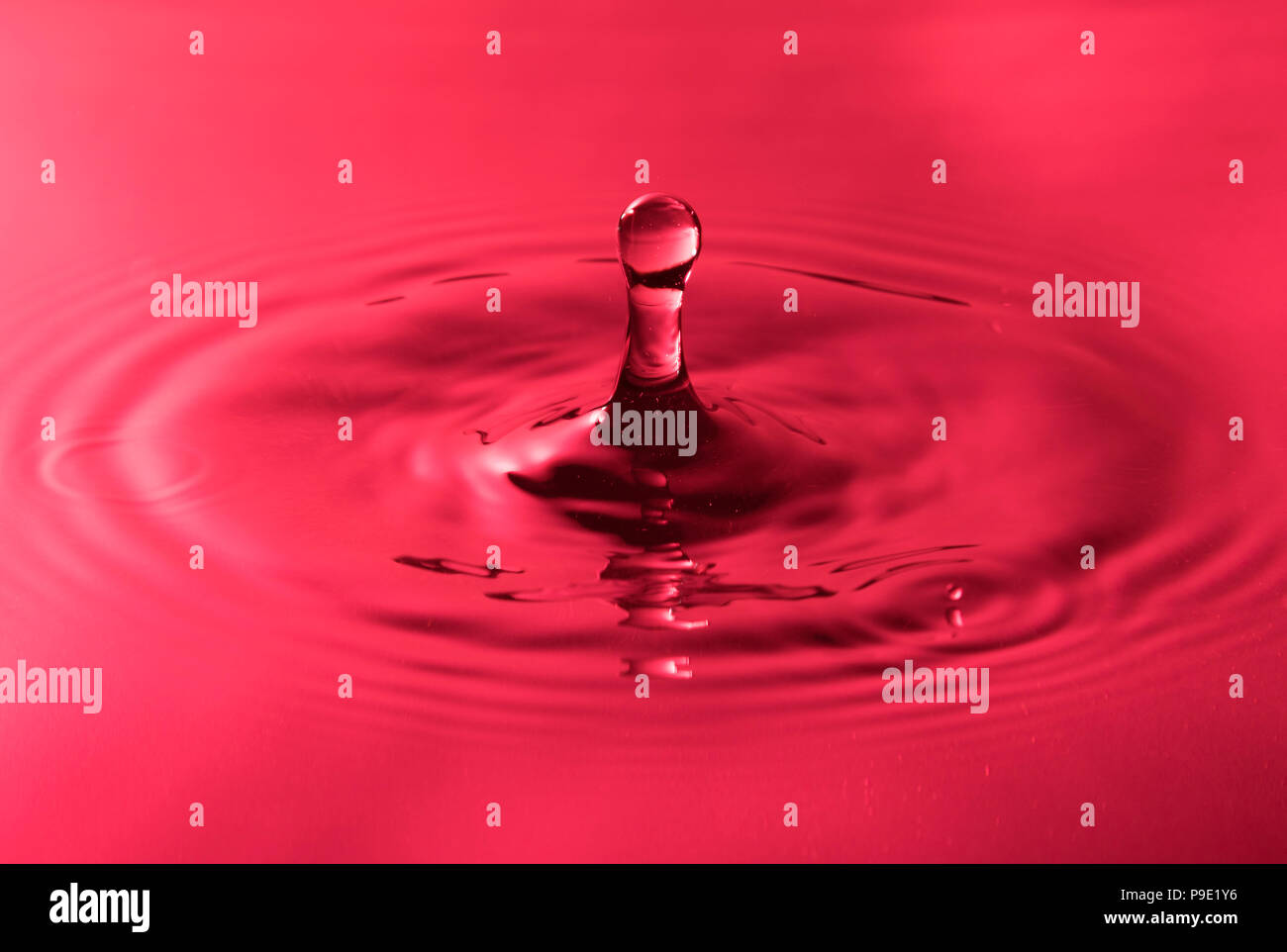 A small water drop fall on water surface and the splash jump to form a ...