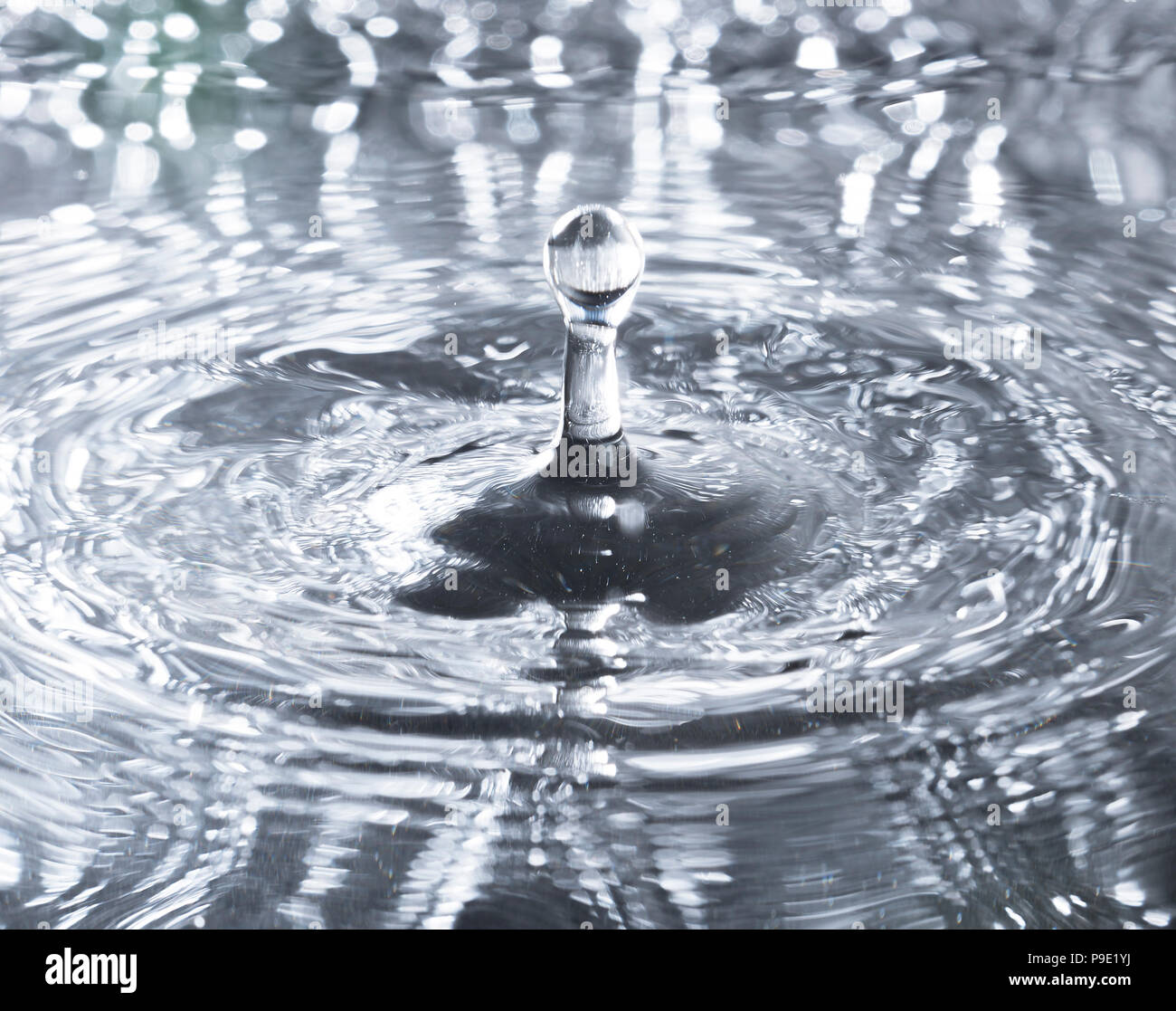 A small water drop fall on water surface and the splash jump to form a ...