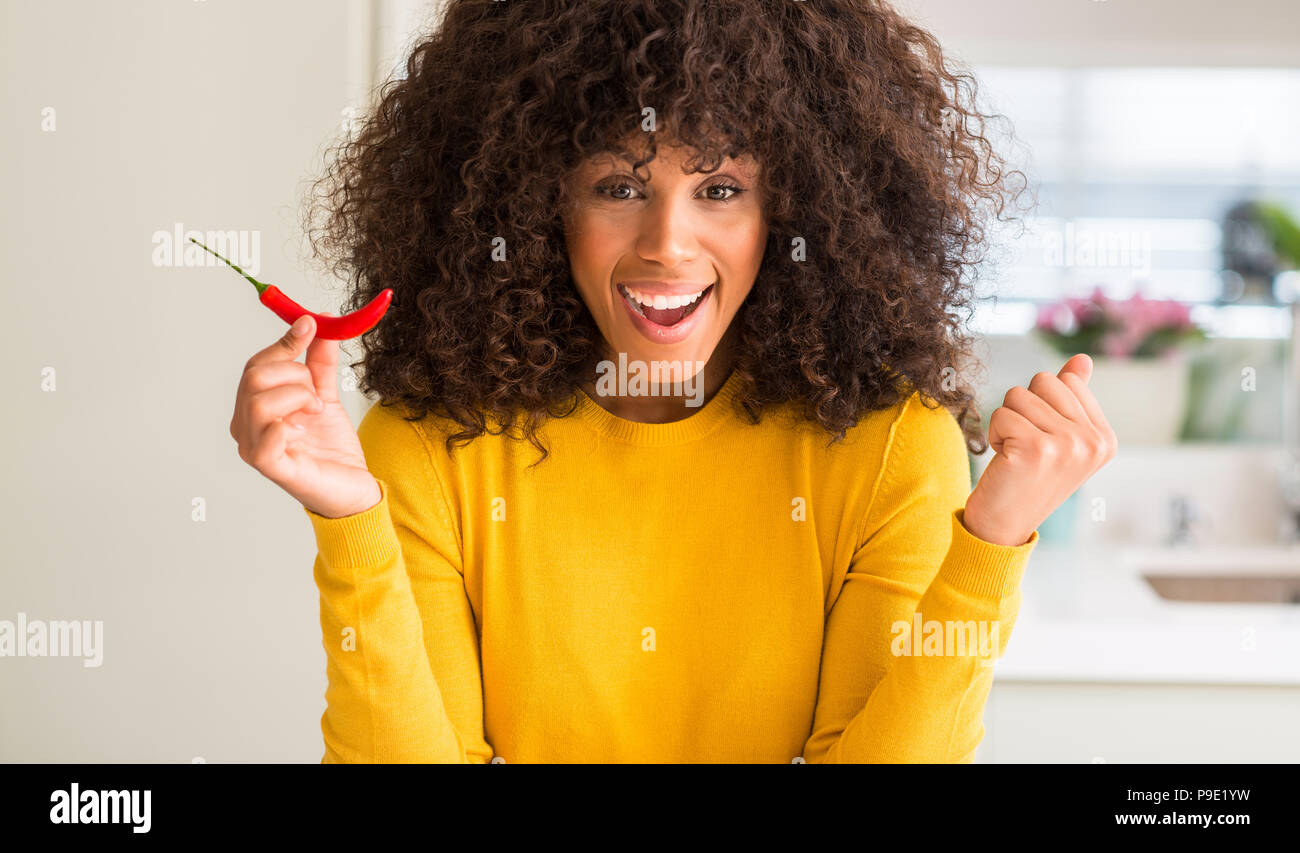 African american woman eating red hot chili pepper screaming proud and ...