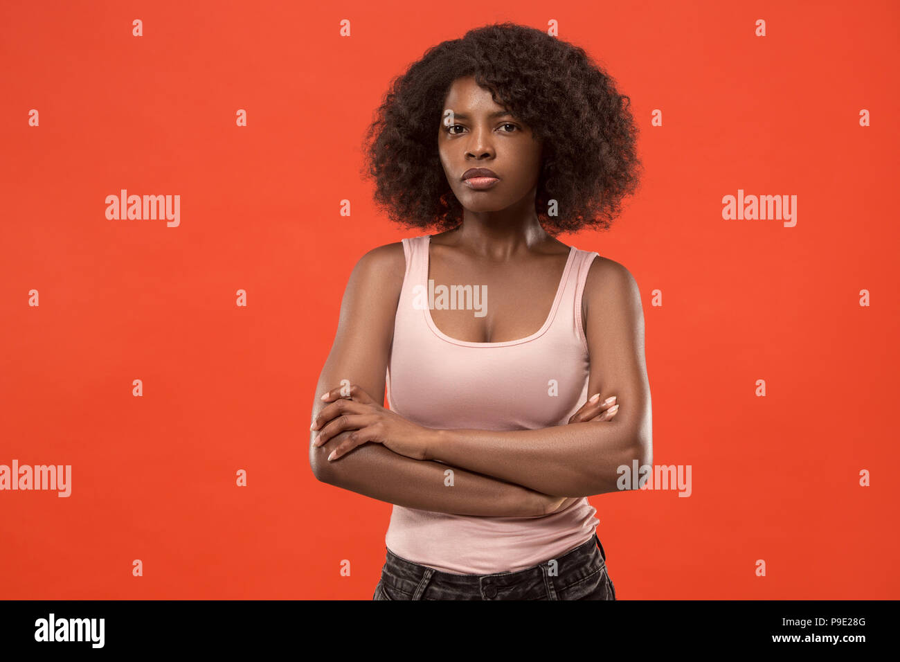 The serious business woman standing and looking at camera against red ...