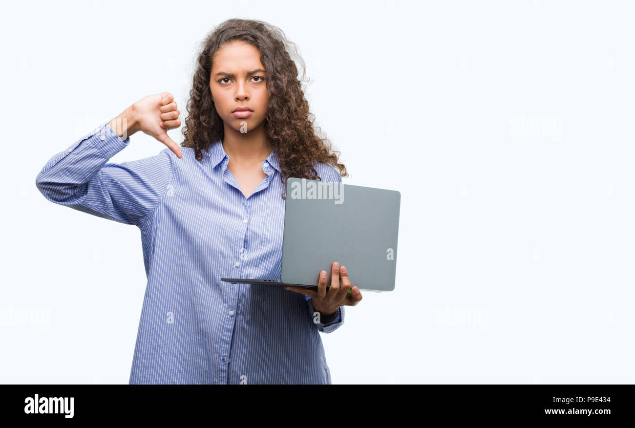Young hispanic woman holding computer laptop with angry face, negative ...