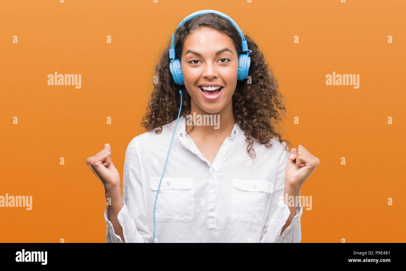 Young hispanic woman wearing headphones screaming proud and celebrating ...
