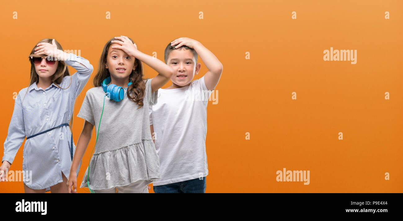 Group of boy and girls kids over orange background stressed with hand ...