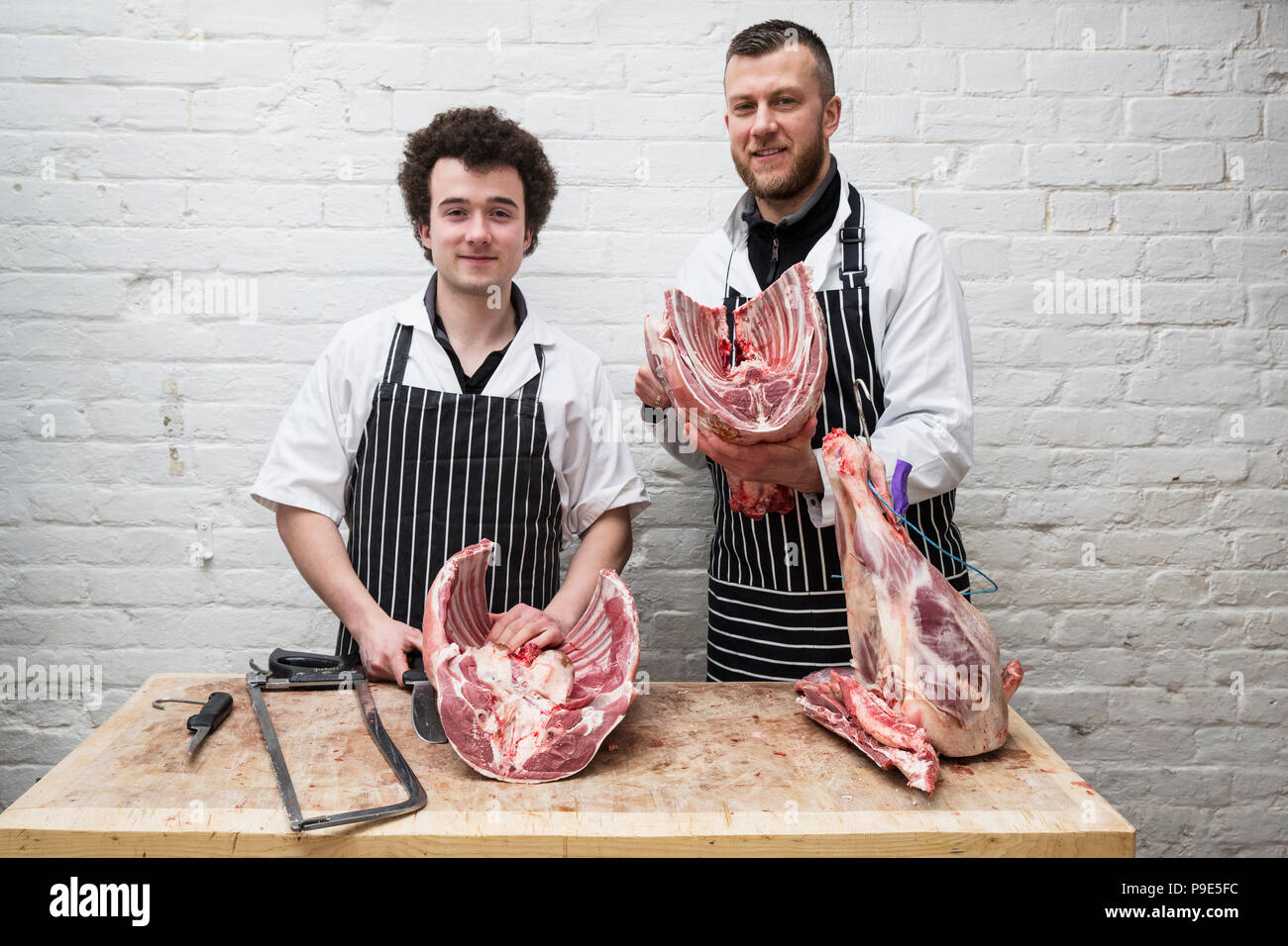 Two butchers side by side holding meat joints, part of a large ...