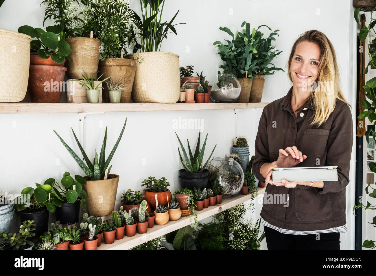 Female owner of plant shop standing next to a selection of plants on ...