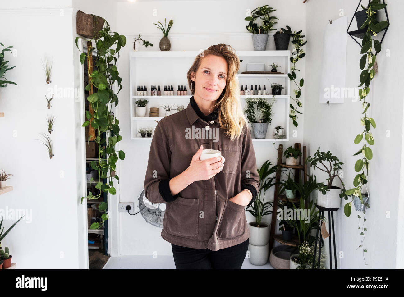 Female owner of plant shop smiling at camera, a selection of plants on ...