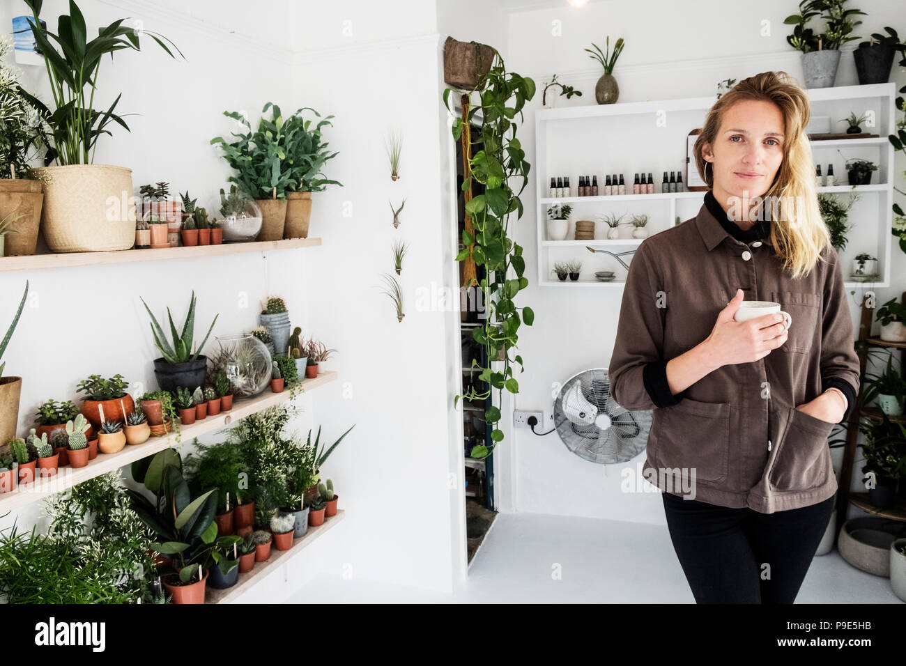 Female owner of plant shop smiling at camera, a selection of plants on ...