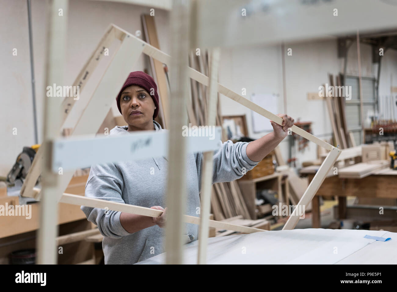 A Black woman carpenter working on a cabinet project in a large ...