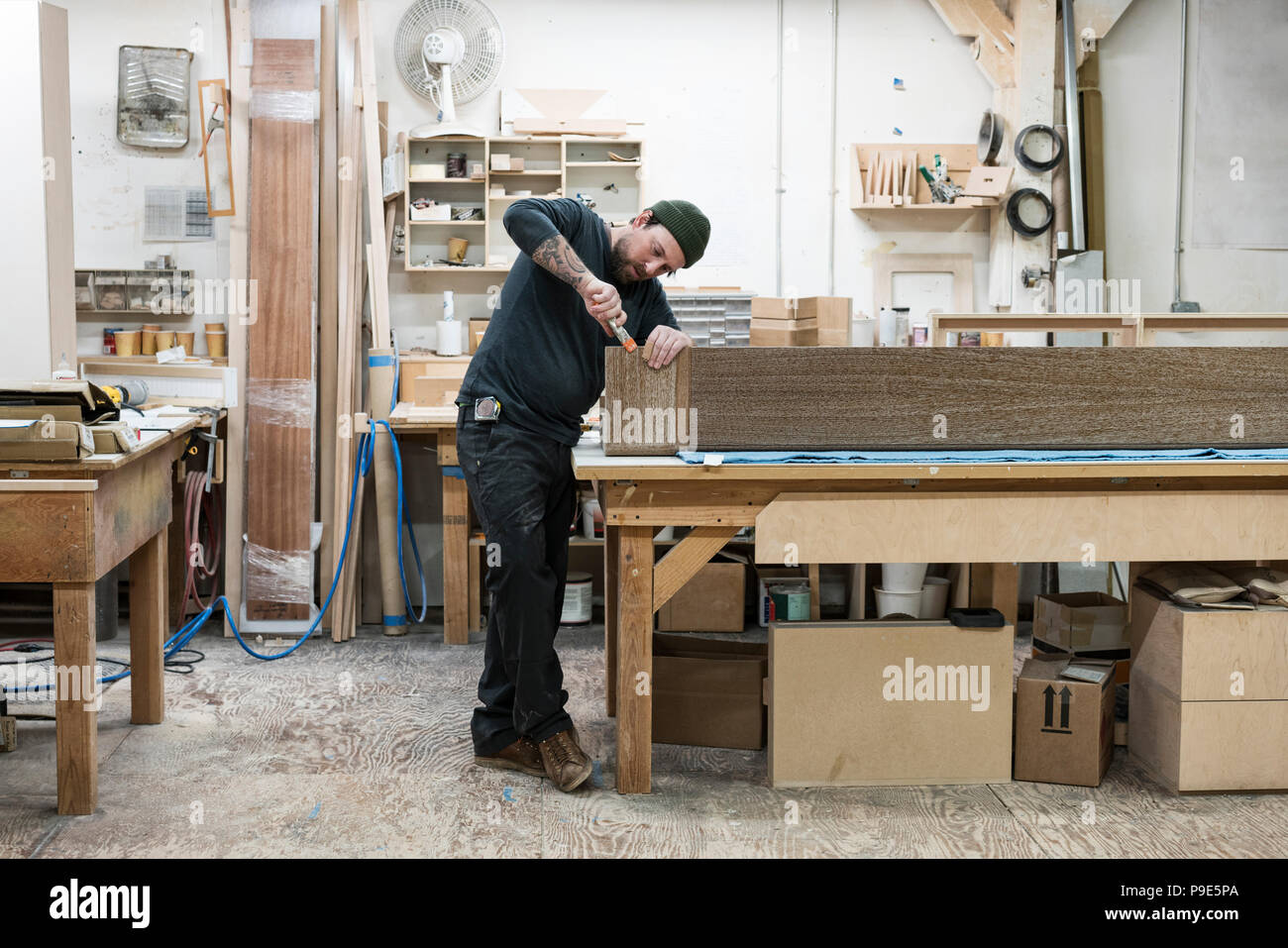 Caucasian male carpenter working on a large cabinet in a woodworking ...