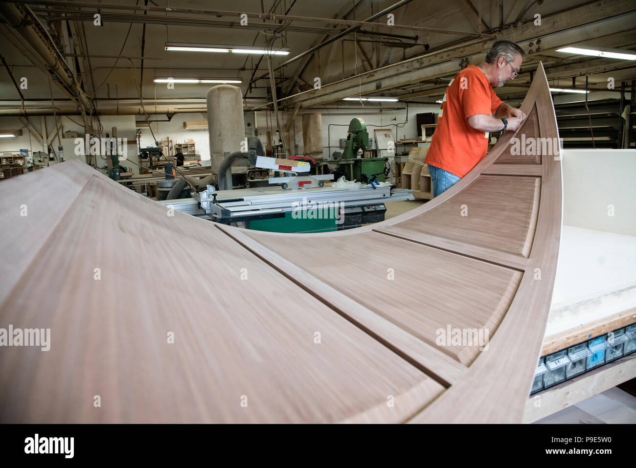 Caucasian carpenter working on curved cabinet face in a large ...