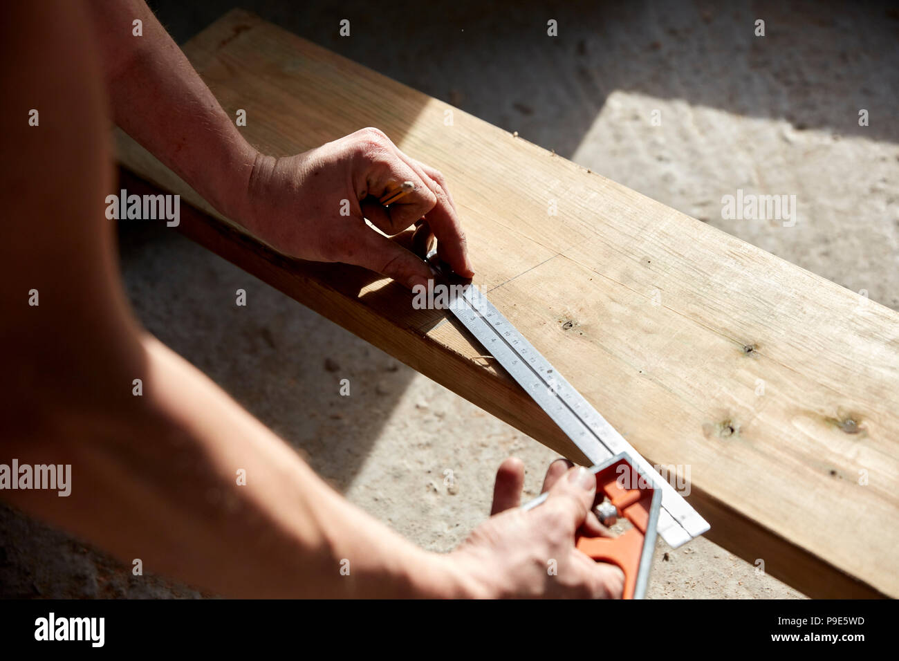 Man measuring a plank of wood using a metal ruler Stock Photo - Alamy