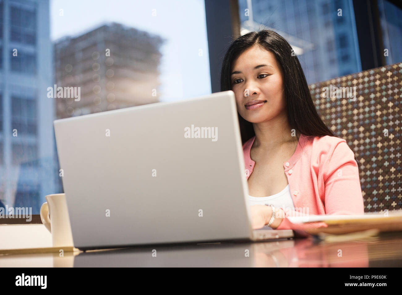 View of an Asian businesswoman working on a laptop computer in her ...