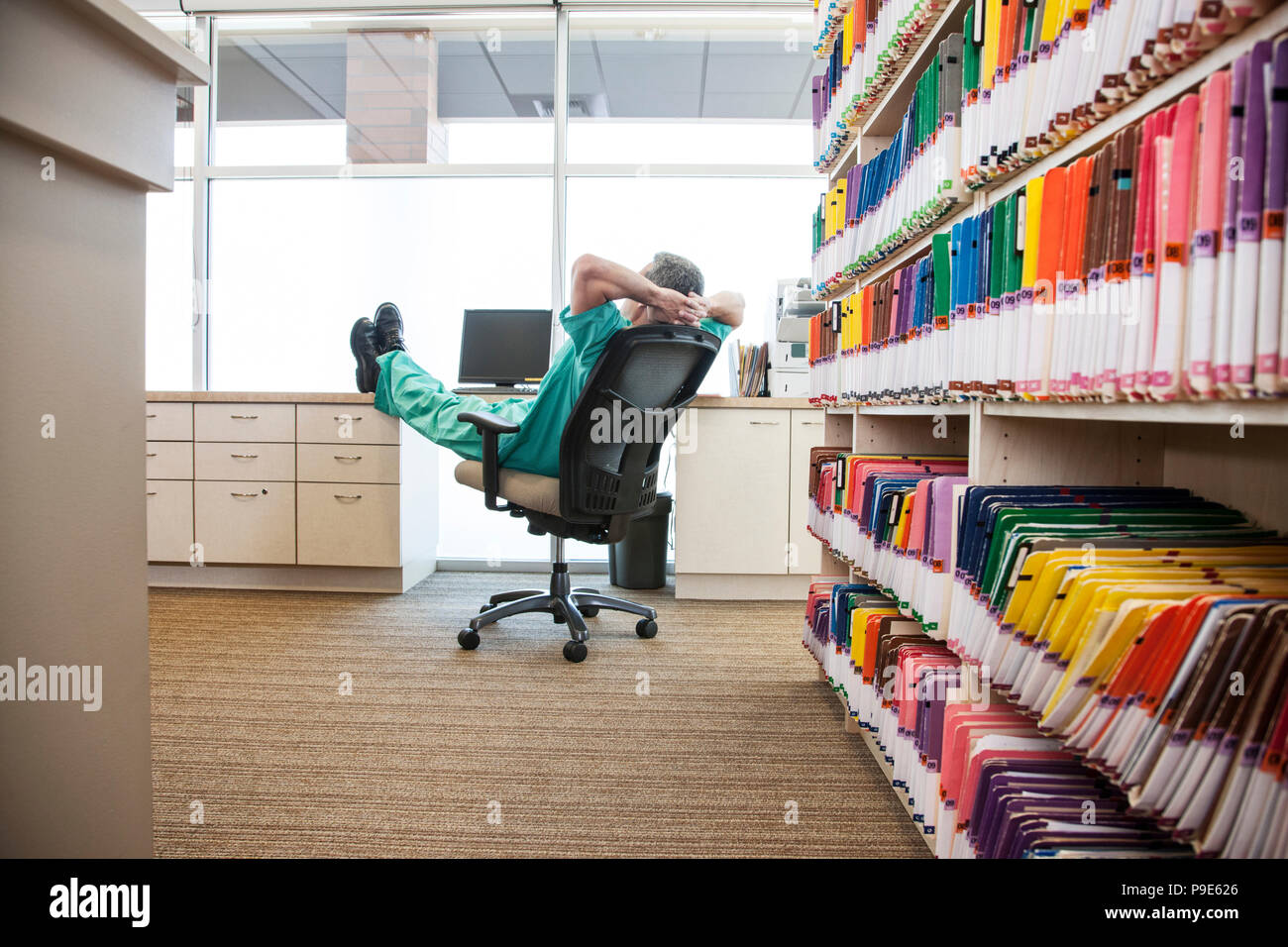 A dentist taking a break with his feet up on a file cabinet Stock Photo ...