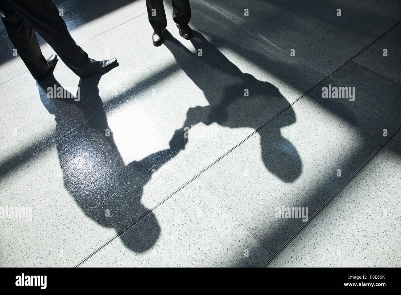 A shadow on a tiled floor of two businessmen shaking hands Stock Photo ...