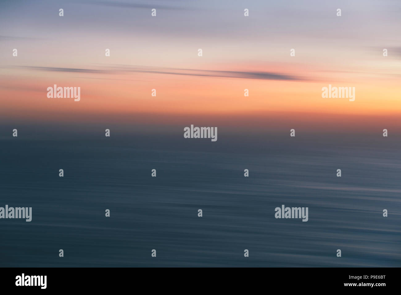 View out to sea over the ocean at dusk, the sunset light on the horizon ...