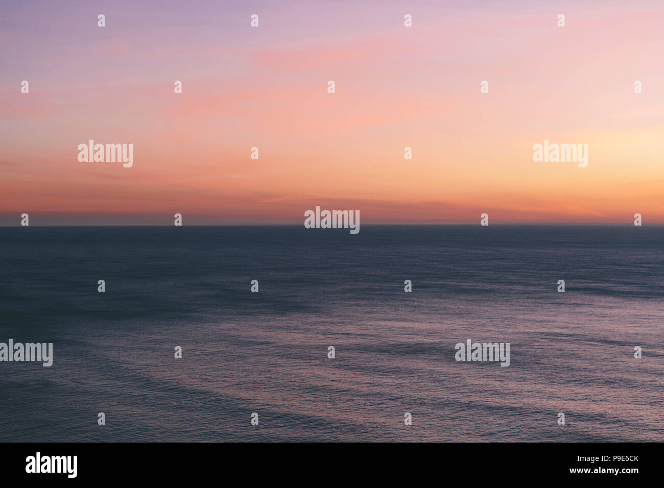 View out to sea over the ocean at dusk, the sunset light on the horizon ...