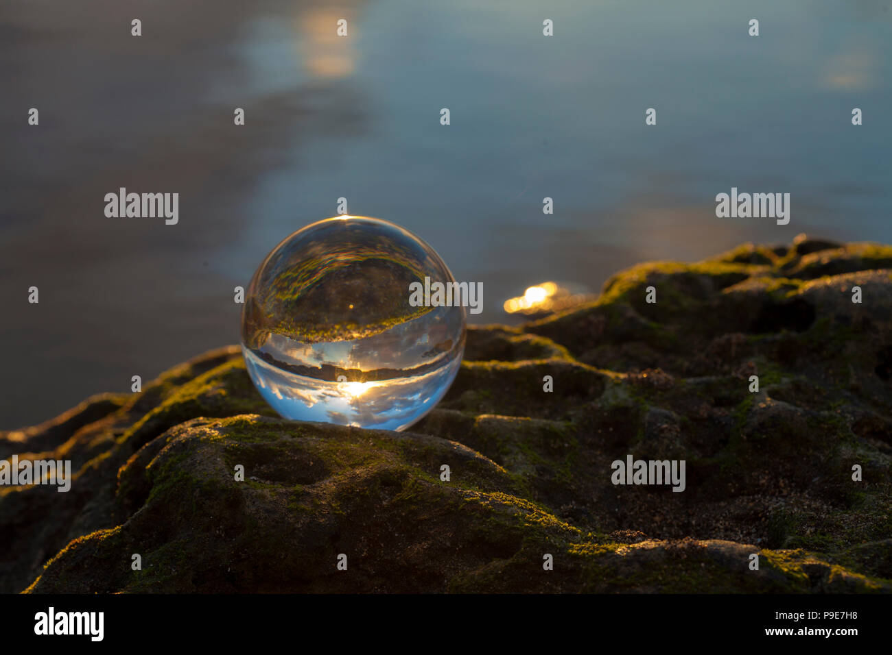 Crystal ball photography - sunset beach, ball on a rock Stock Photo - Alamy