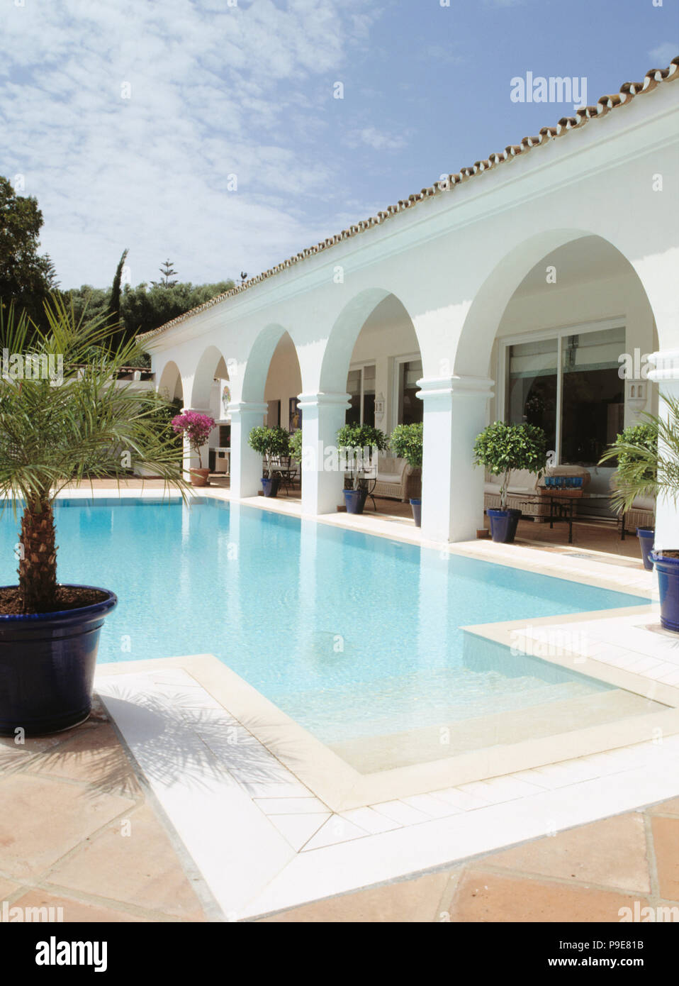 Spanish villa with arched veranda opening onto turquoise swimming pool ...