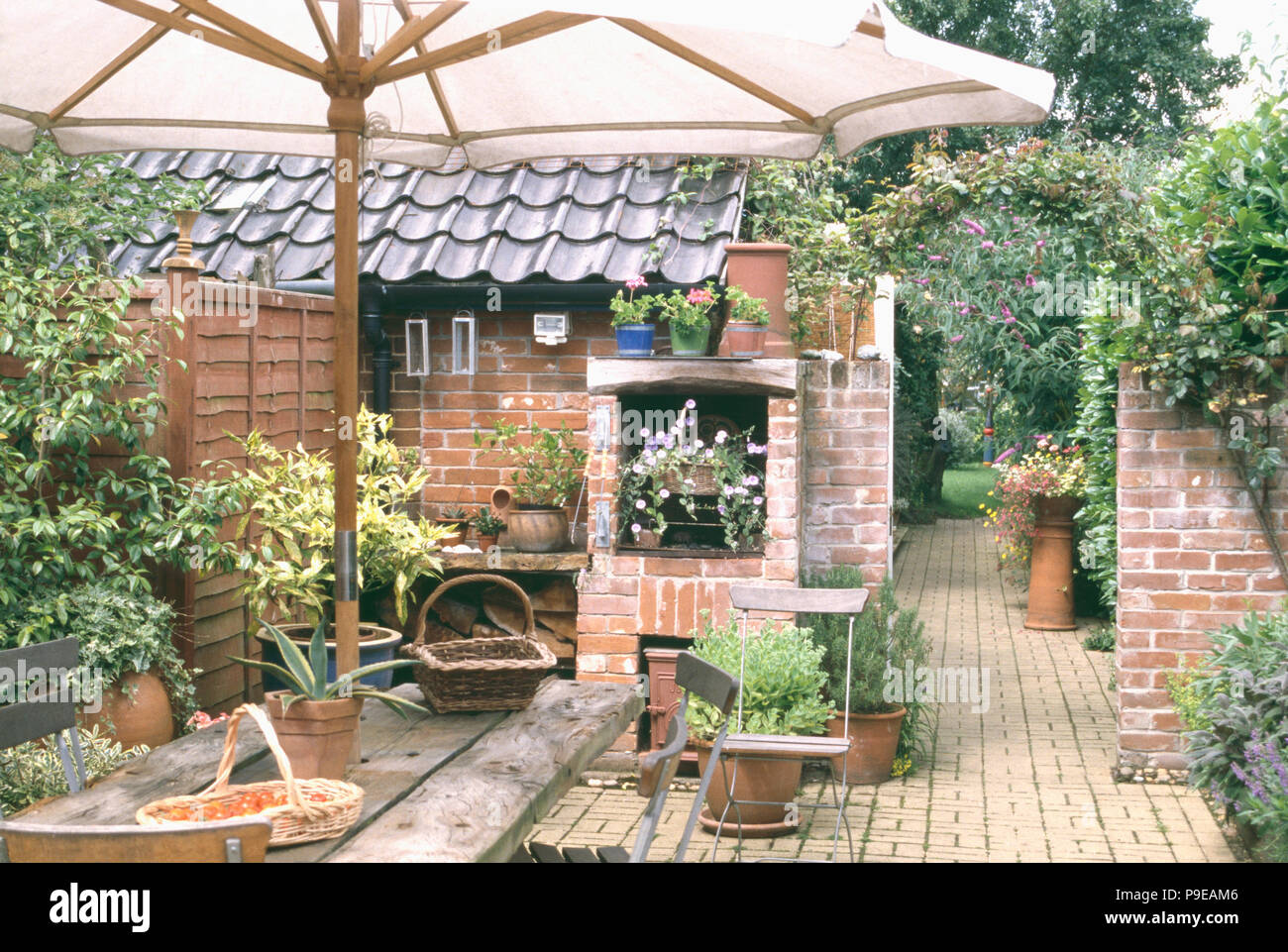 Wooden table below white parasol in small courtyard in country garden ...