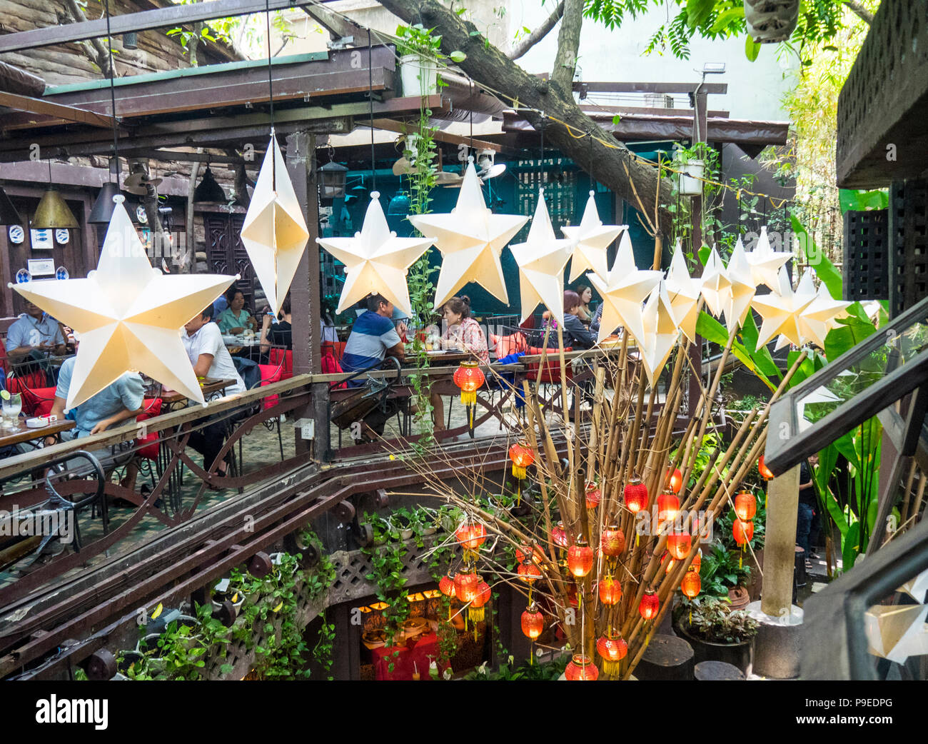 Diners on the wooden decking in the garden of the Tram Cafe in Ho Chi ...