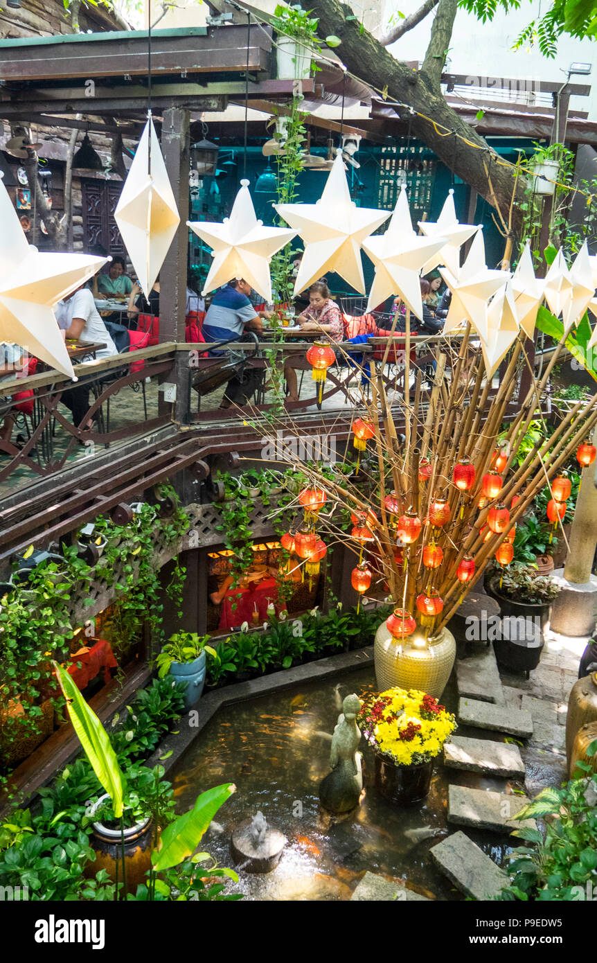 Diners on the wooden decking in the garden of the Tram Cafe in Ho Chi ...