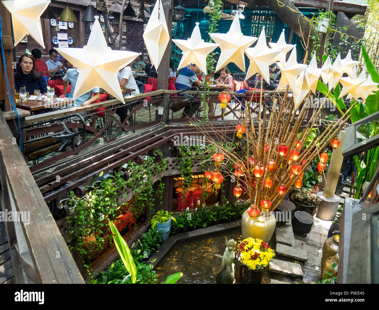 Diners on the wooden decking in the garden of the Tram Cafe in Ho Chi ...
