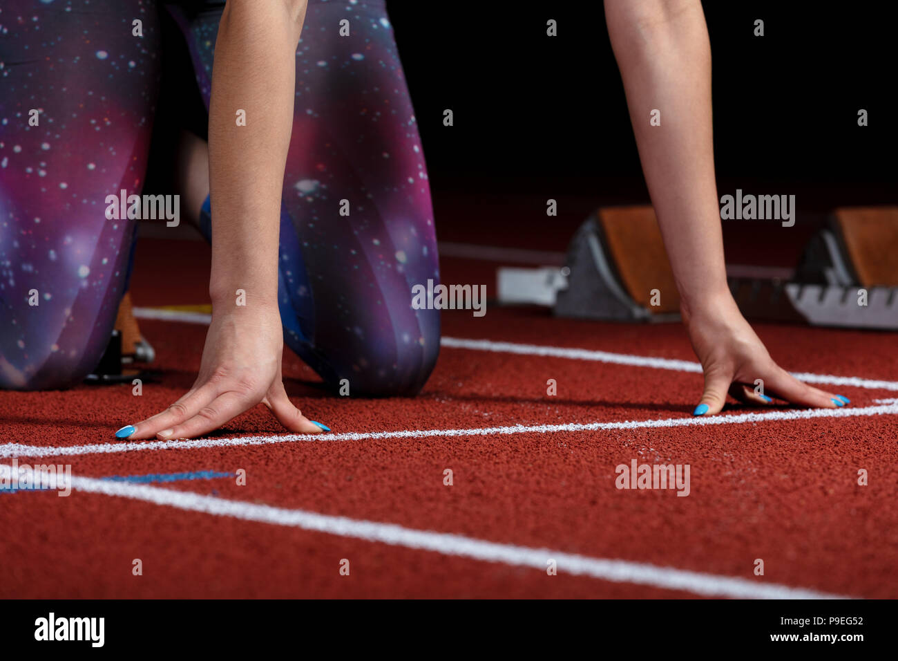woman sprinter leaving starting blocks on the athletic track. exploding ...