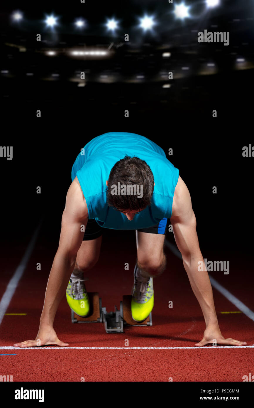 Sprinter leaving starting blocks on the running track in front of big ...