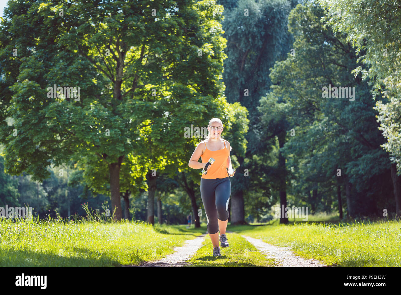 Young girl running down a path on meadow with weight dumbbells Stock ...