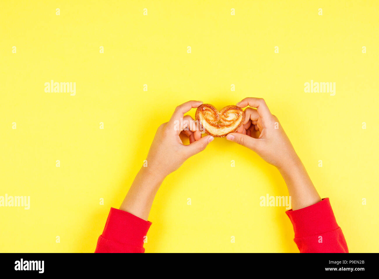 Kid hands holding cookie over yellow background Stock Photo - Alamy