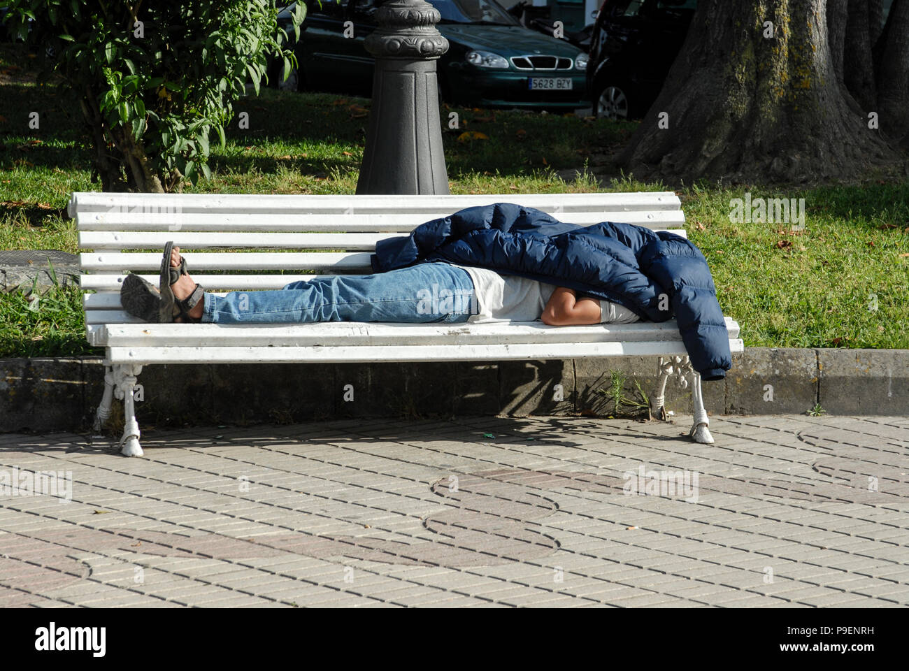A local man taking a siesta, covering his face with his jacket as a ...