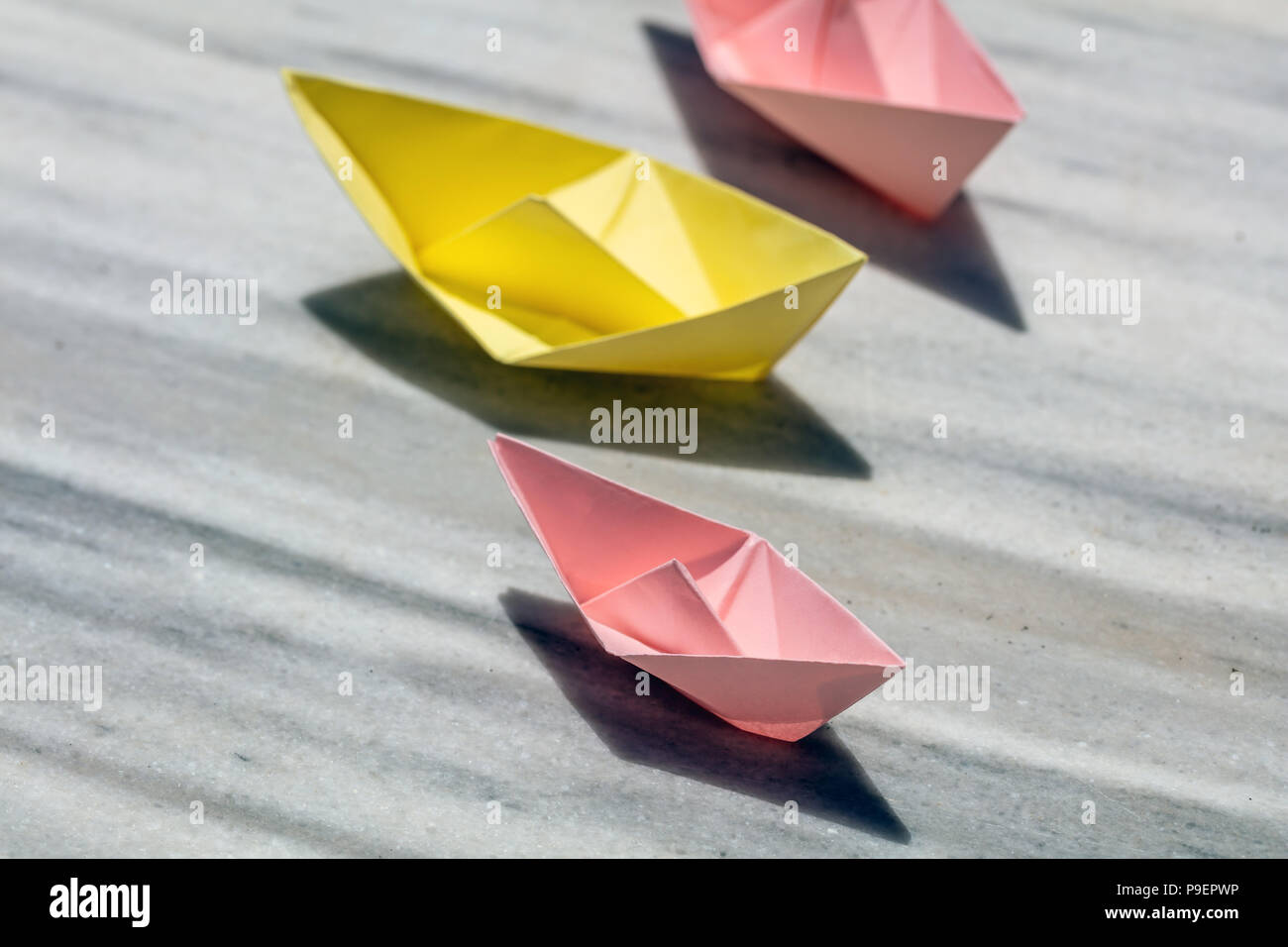 Pink and yellow paper folded, origami, boats on a rock, copy space ...