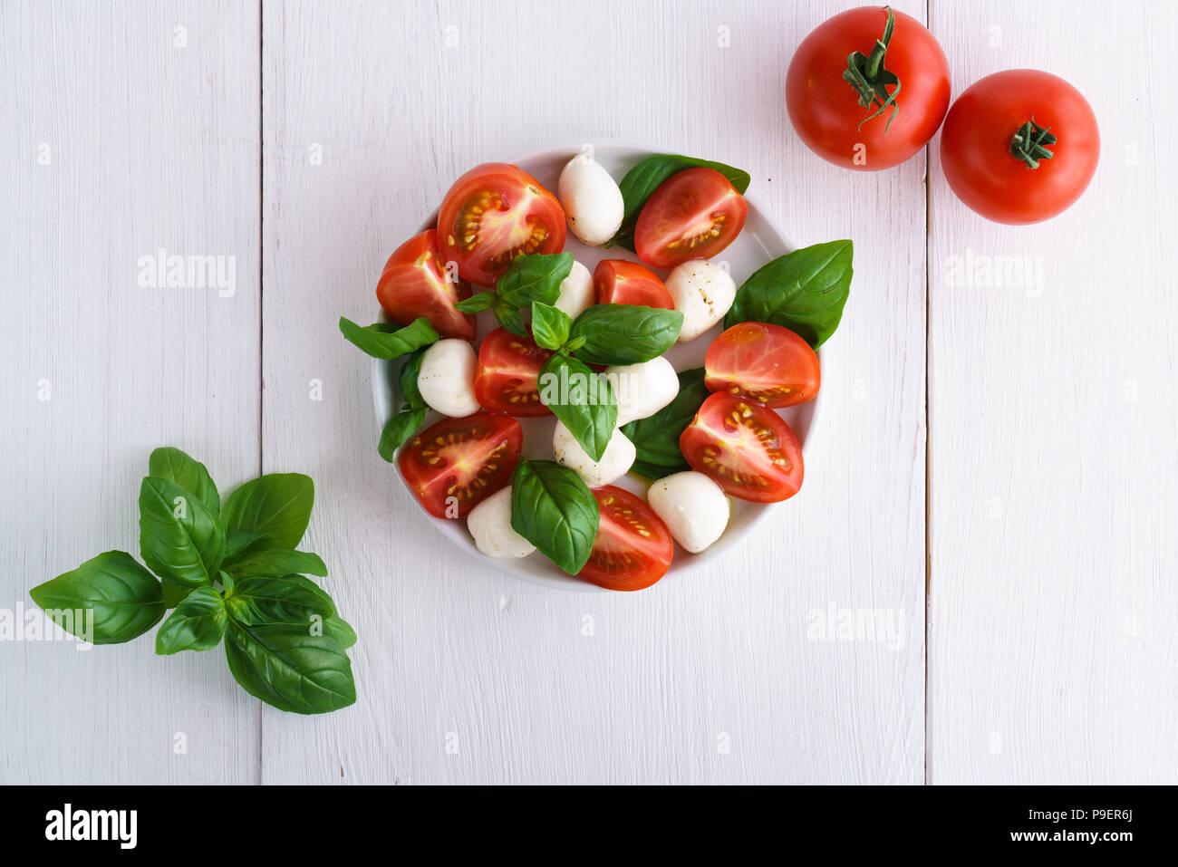 Caprese salad served on a white ceramic plate. White wooden background ...