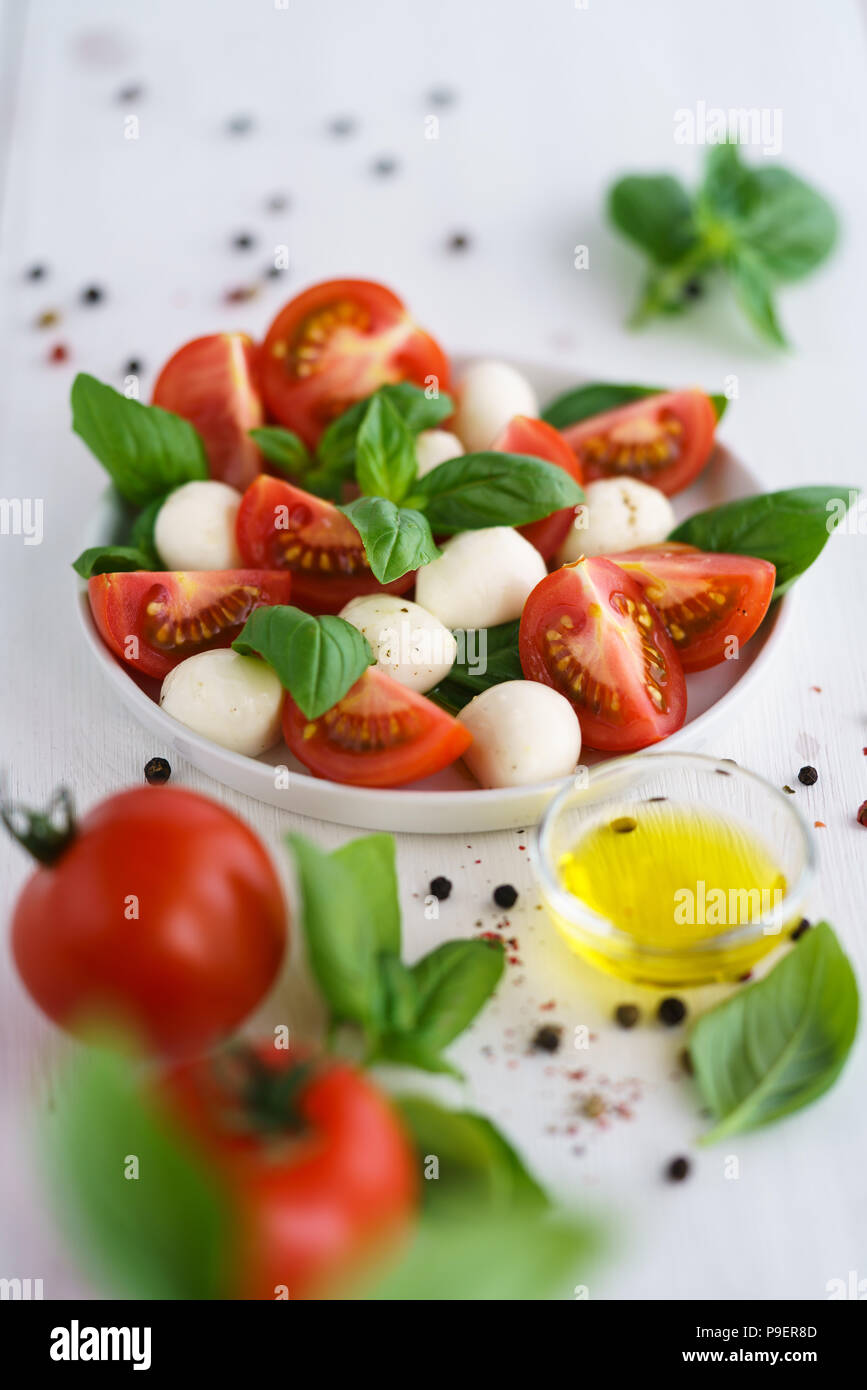 Caprese salad served on a white ceramic plate. White wooden background ...
