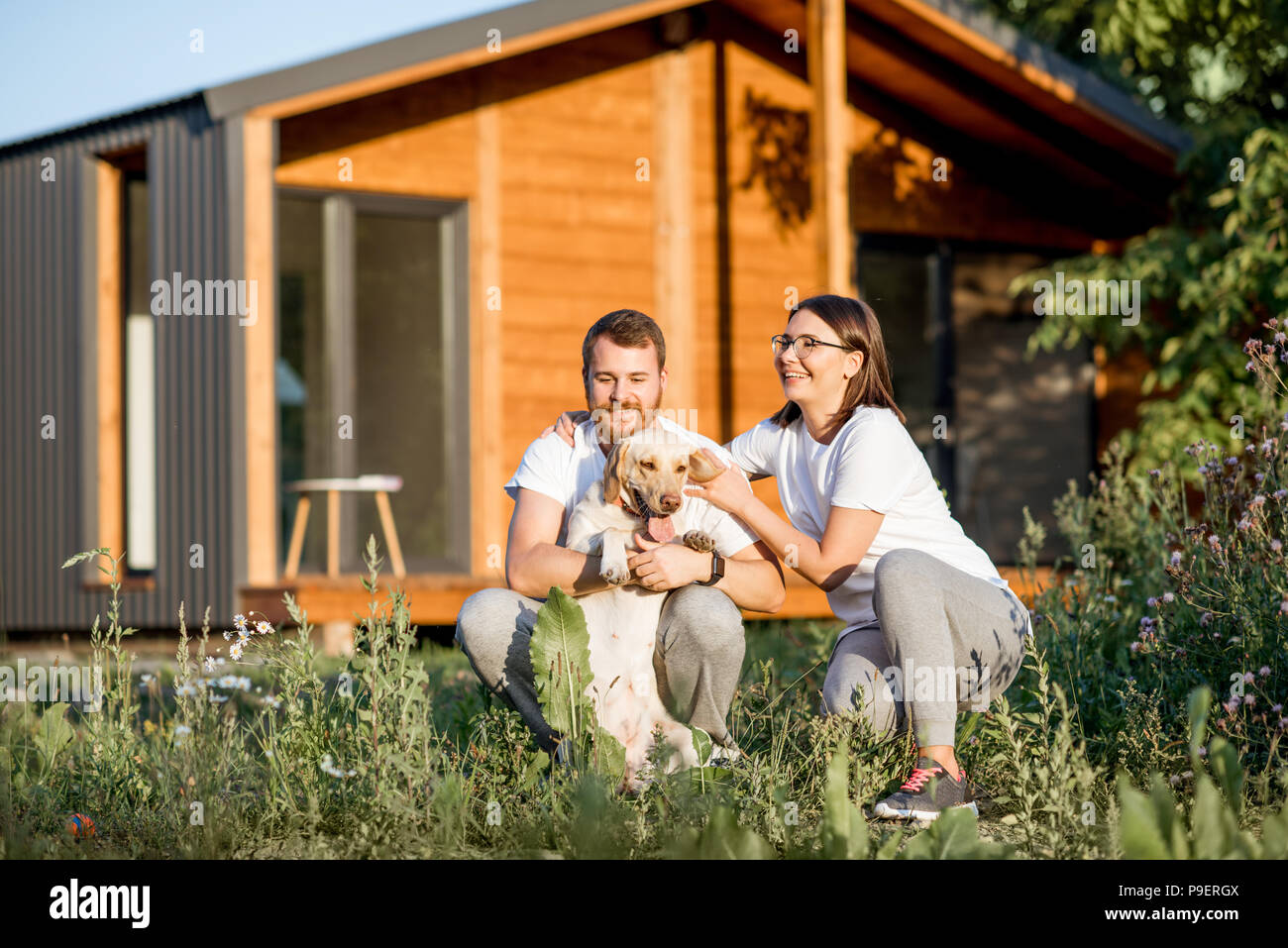 Couple with dog on the backyard of the house Stock Photo - Alamy