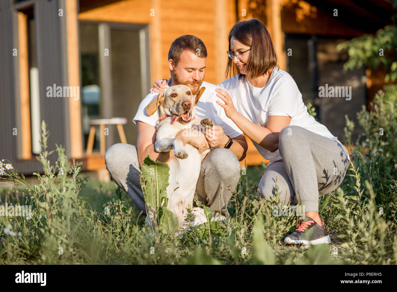 Couple with dog on the backyard of the house Stock Photo - Alamy