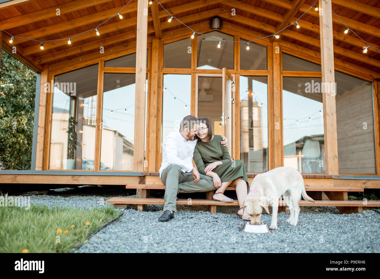 Couple with dog near the house Stock Photo - Alamy