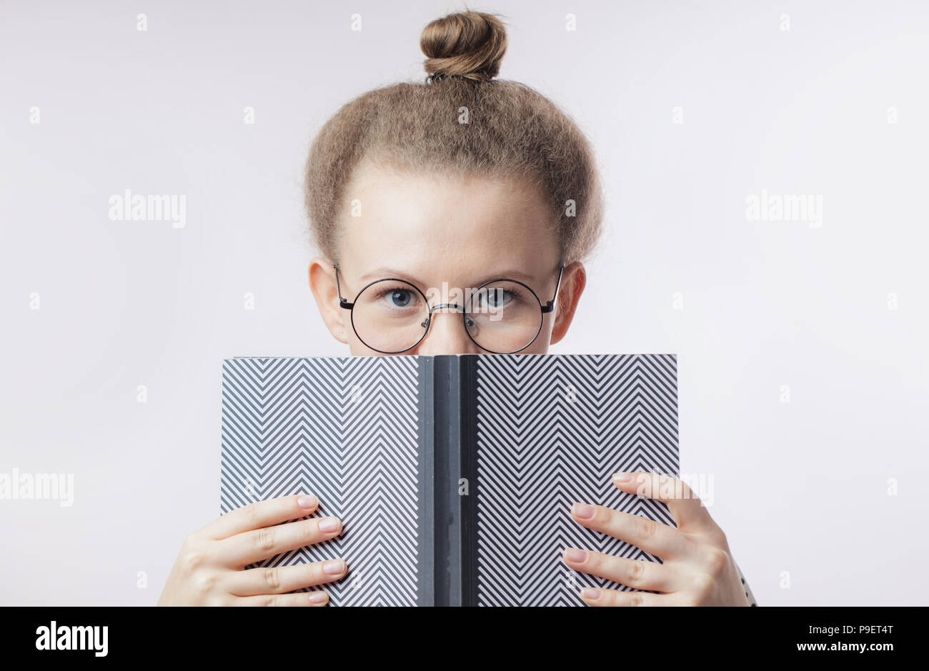 scared girl hiding behind the book. school and univercity concept ...
