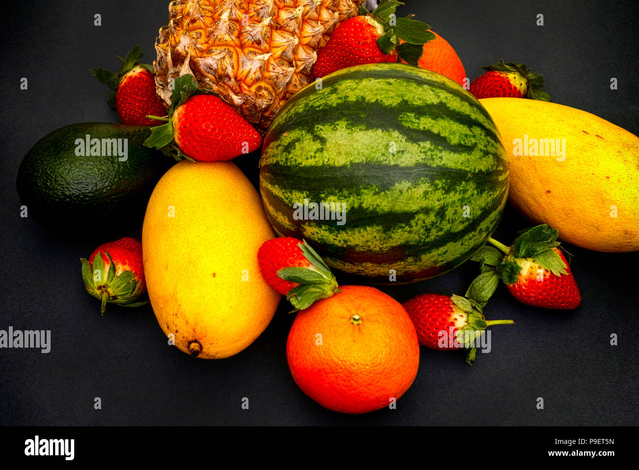Watermelon, mango, strawberry, mandarin, pineapple and avocado on black ...