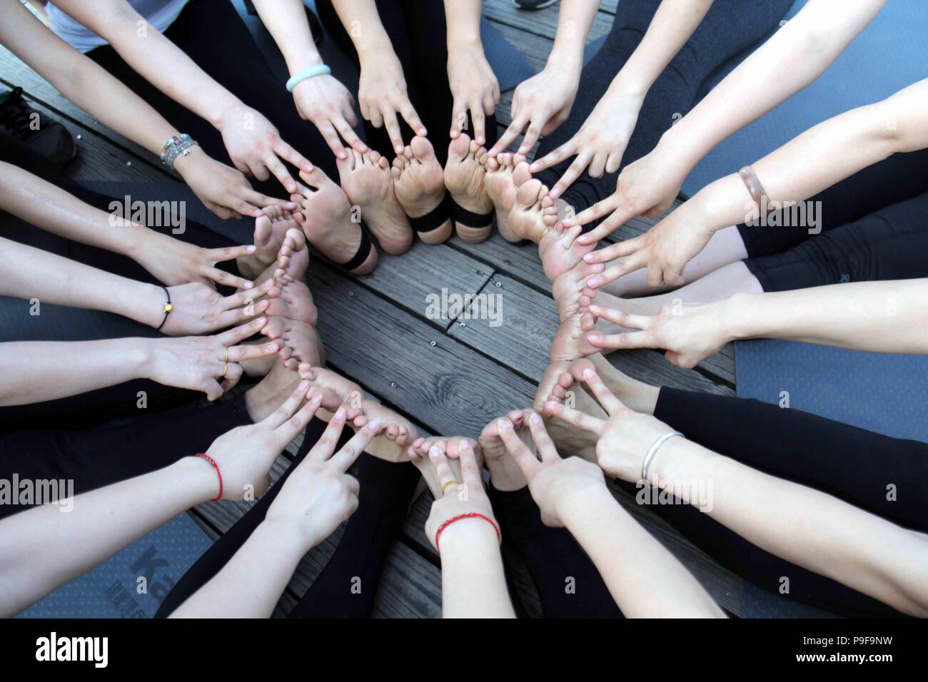 Wuhu, China. 18th July, 2018. Women in a circle touch their toes as ...