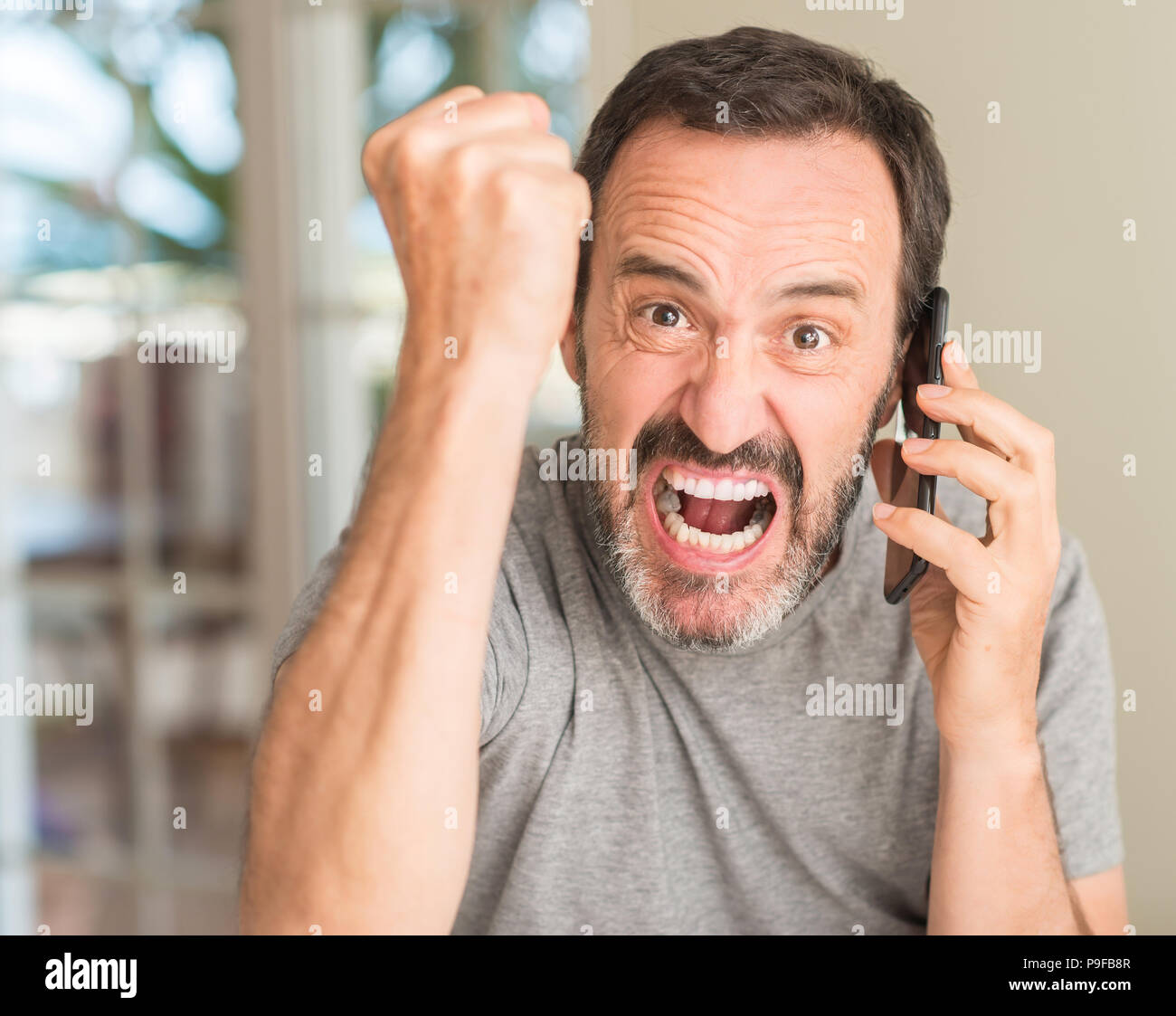 Middle age man using smartphone annoyed and frustrated shouting with ...