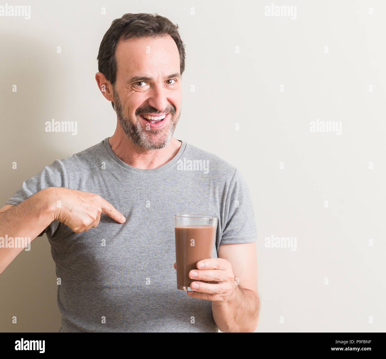 Senior man drinking chocolate milk shake with surprise face pointing ...