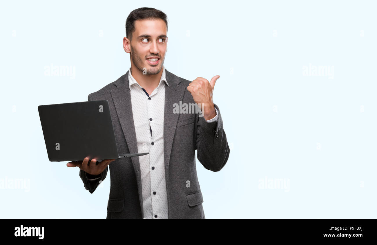Handsome young man using computer laptop pointing with hand and finger ...